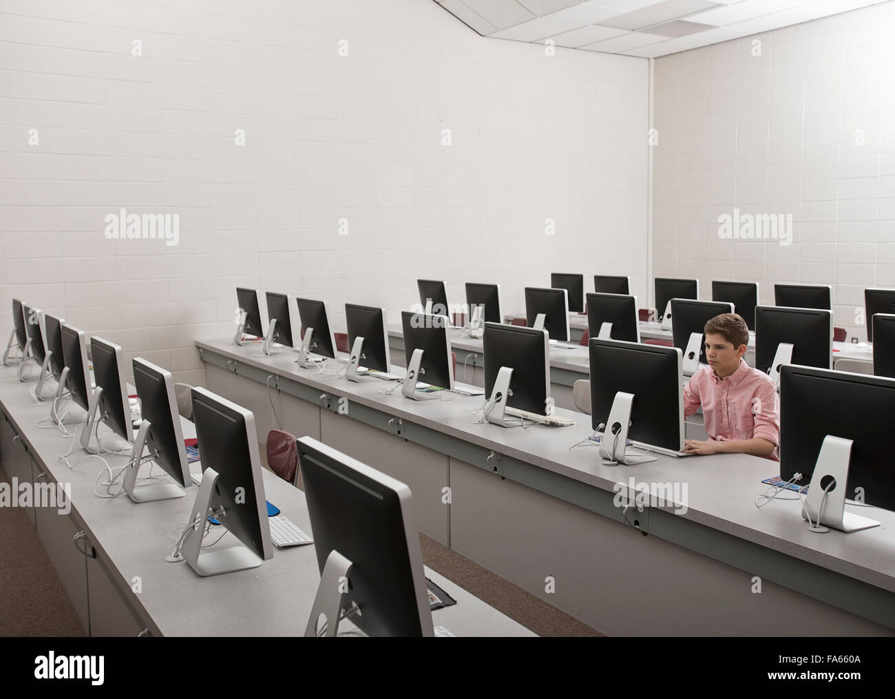 A school room, a computer lab with rows of screens and seating. A young ...
