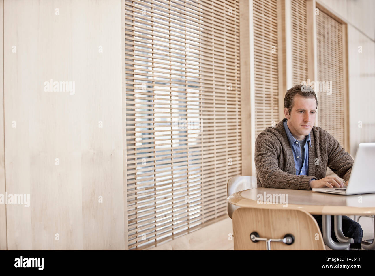 A man sitting at a table on a terrace using a computer laptop Stock ...