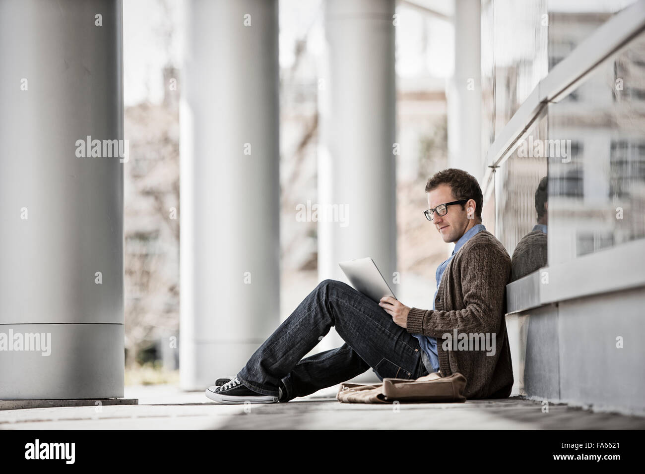 A man sitting outside a building on steps using a digital tablet Stock ...