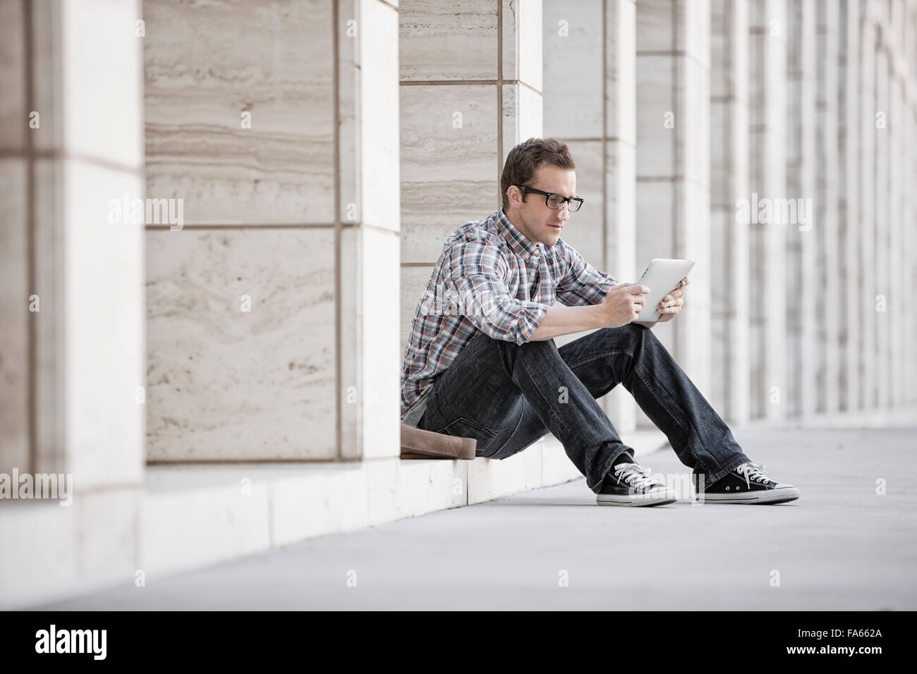 A man relaxing and checking his phone, sitting outside a building Stock ...