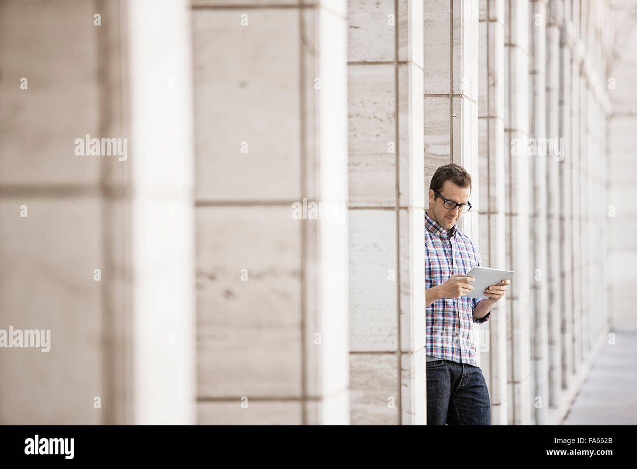 A man relaxing and checking his phone, sitting outside a building Stock ...