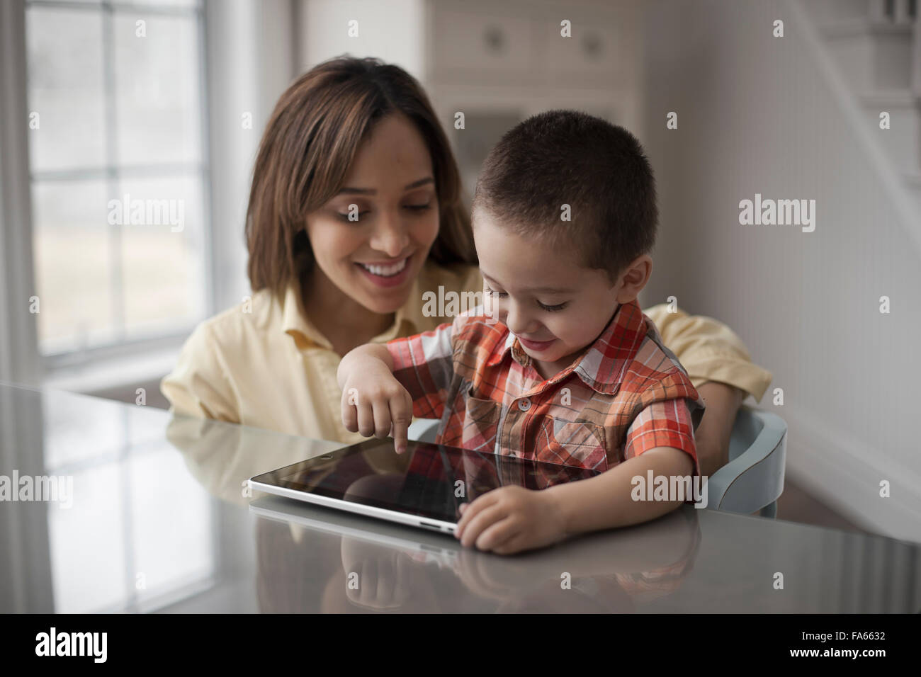 A mother and child looking at the screen of a digital tablet, the boy ...