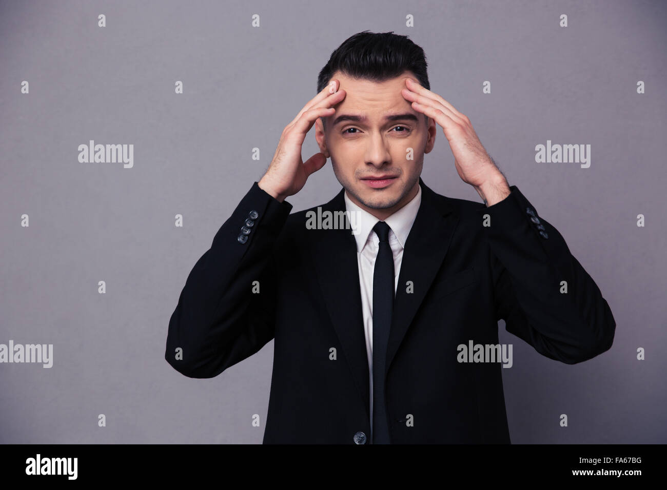 Portrait of a young businessman thinking over gray background Stock ...