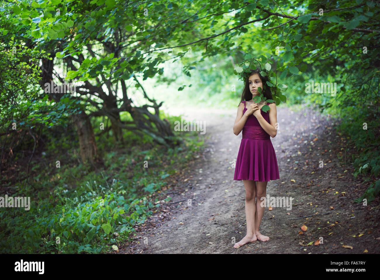 Portrait of a girl standing in road wearing headdress made of leaves ...