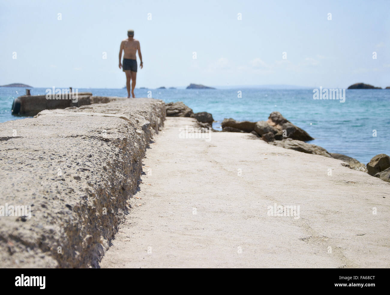 Rear view of man walking along wall by beach, Ibiza, Spain Stock Photo ...
