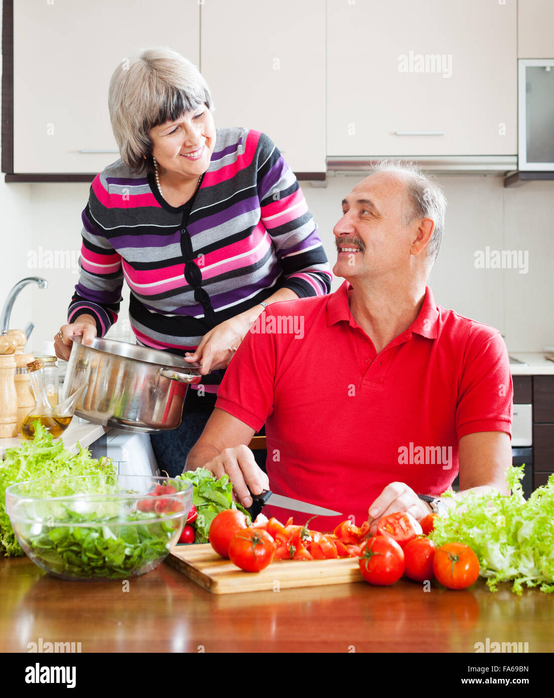 loving mature couple cooking with tomatoes in kitchen at home Stock ...