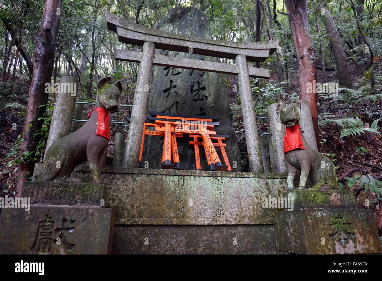 A shrine with fox sculptures, and red torii gate offerings at Fushimi ...