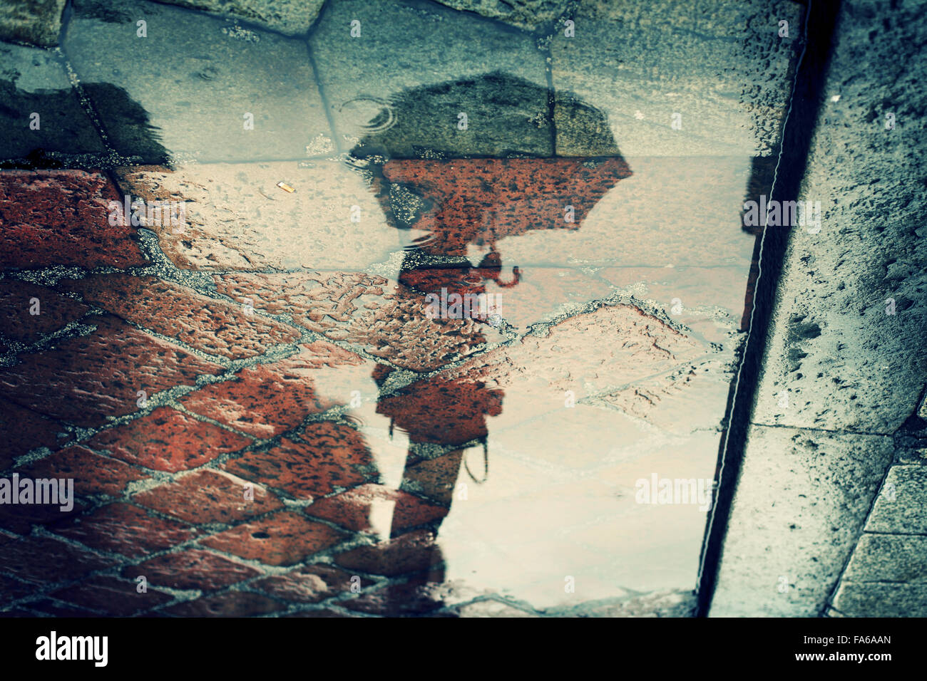 Reflection in a puddle of a person holding an umbrella Stock Photo - Alamy