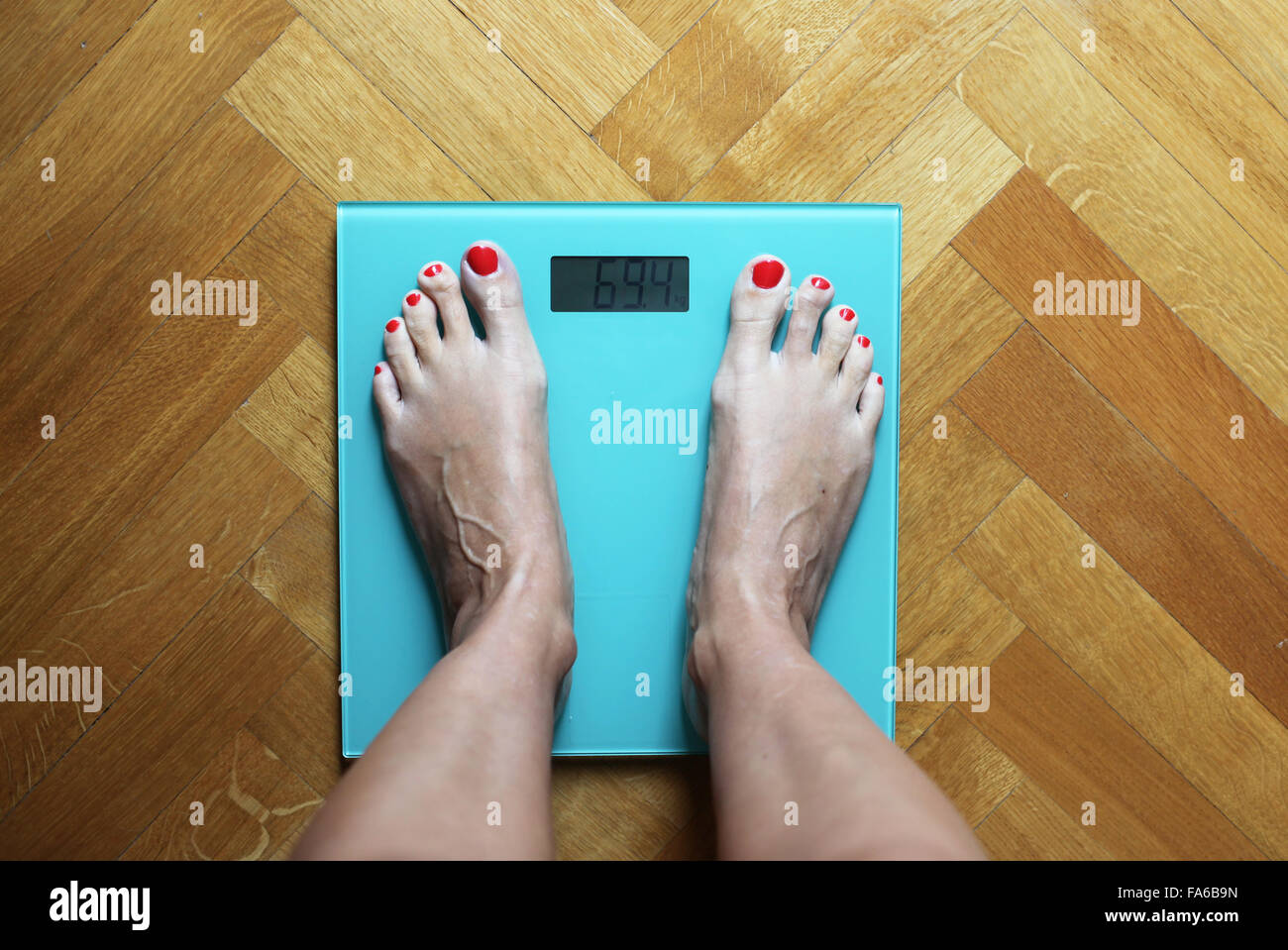 Woman standing on weighing scales Stock Photo - Alamy