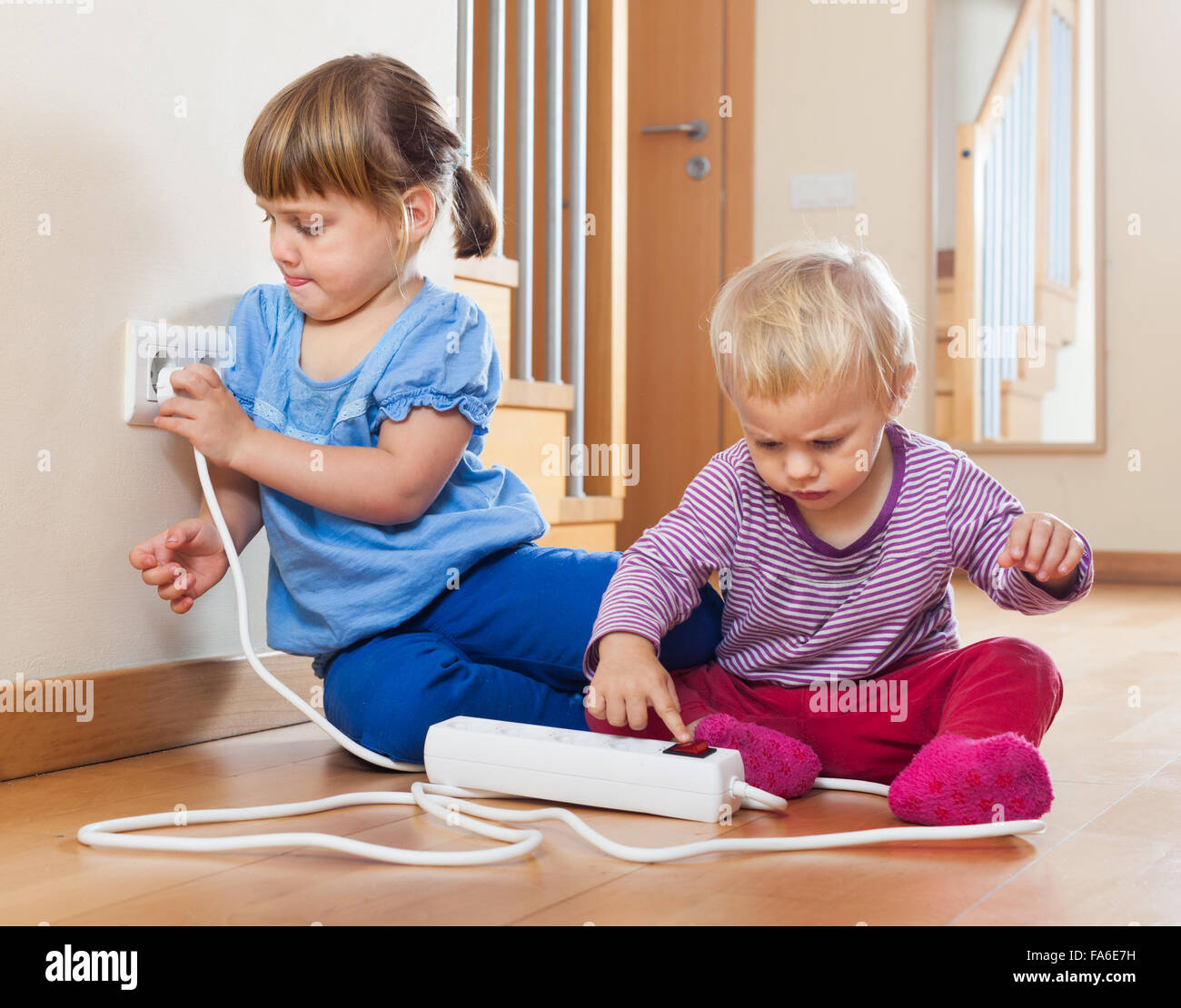 Two children playing with electrical extension and outlet on floor at ...