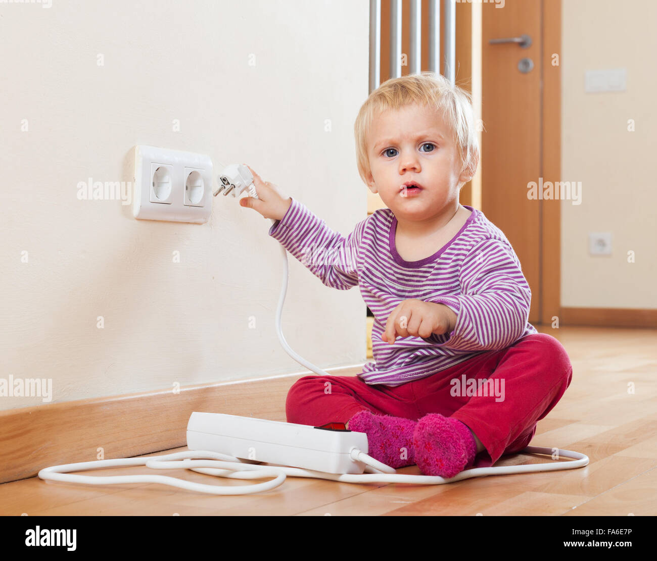 Baby playing with electrical extension and outlet on floor Stock Photo ...