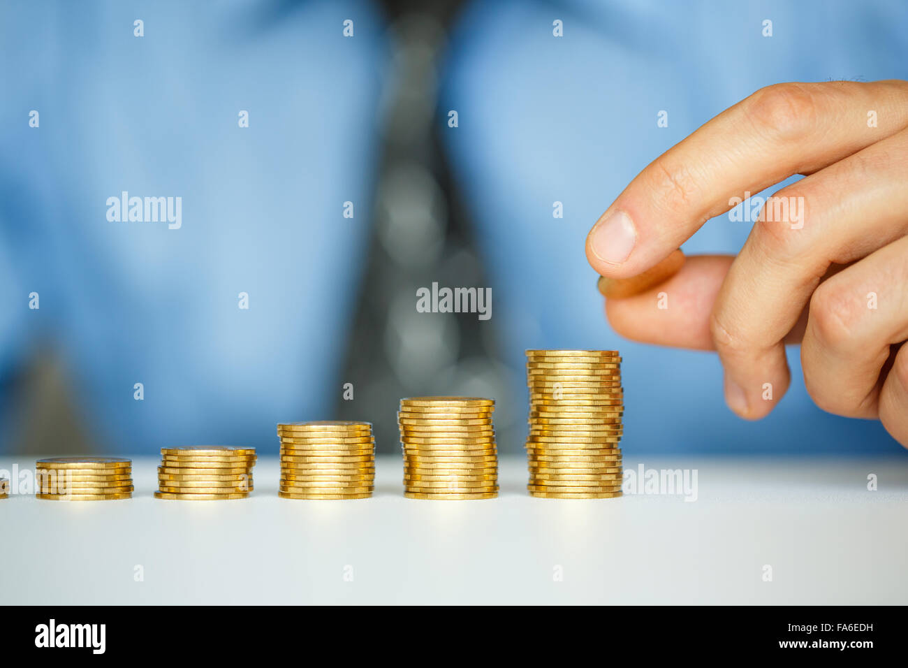 Savings, male hand stacking gold coins into increasing columns Stock ...