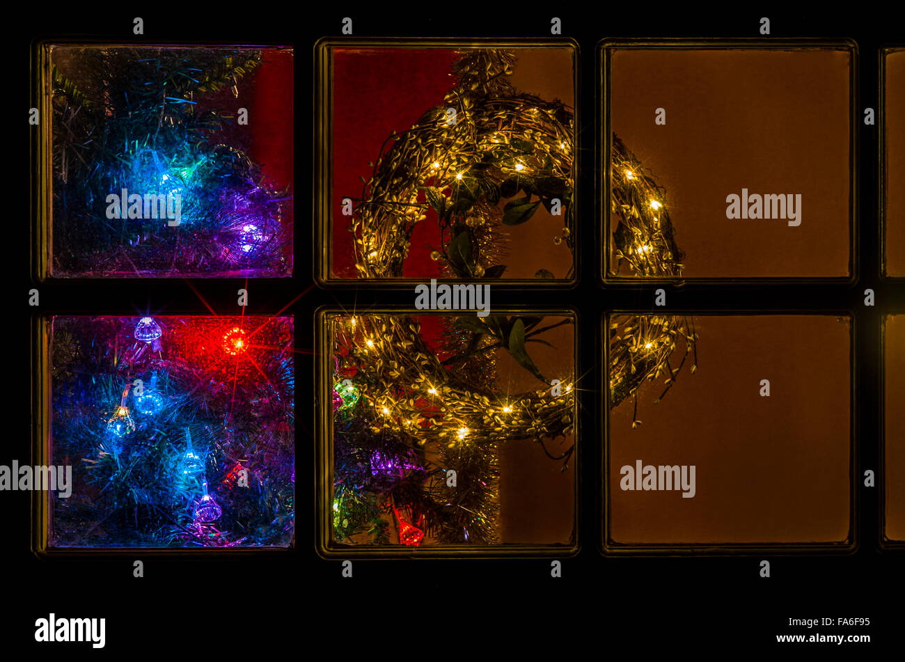 Illuminated wreath and Christmas tree lights through a lodge window ...