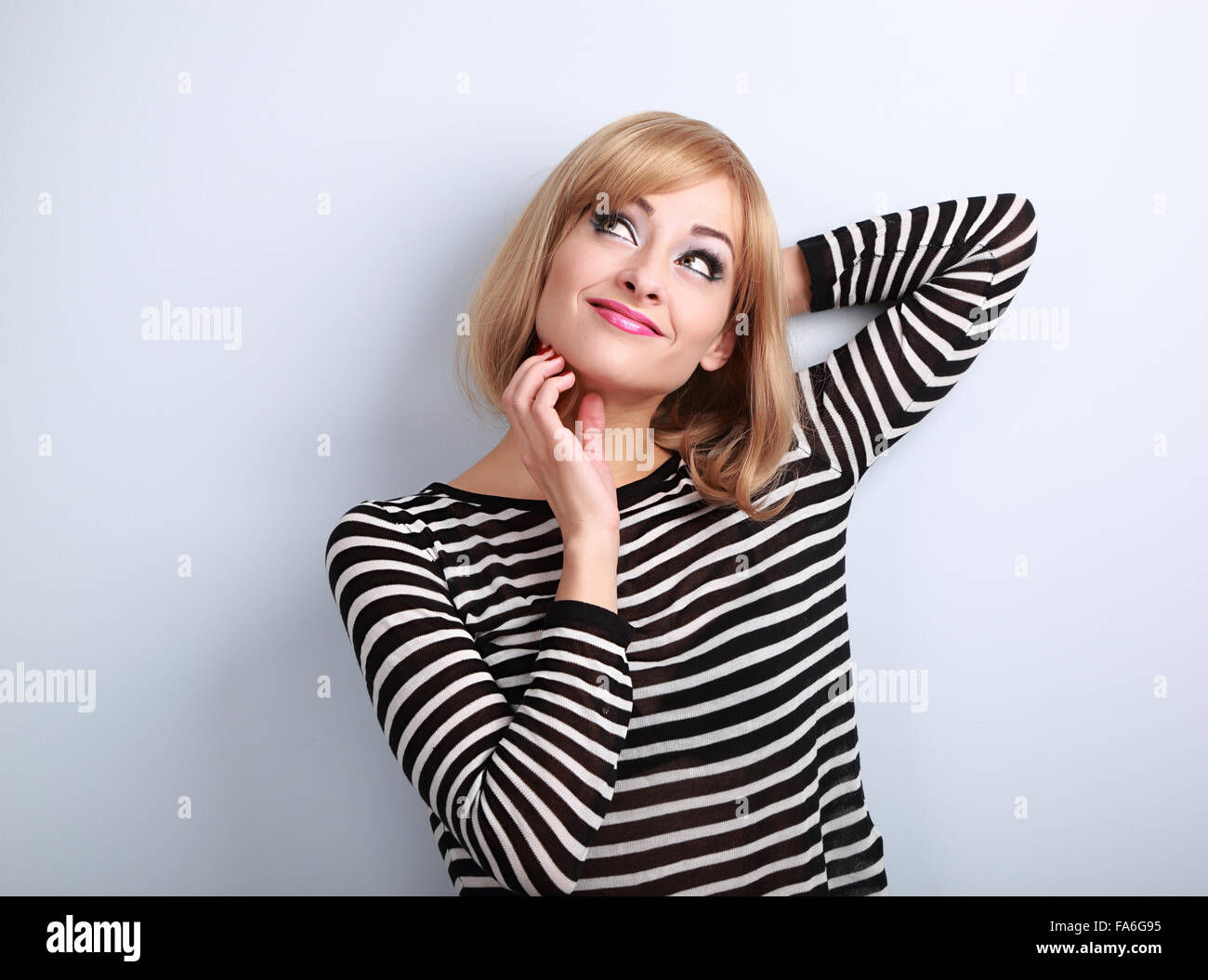 Thinking casual blond woman scratching the chin and relaxing looking up ...