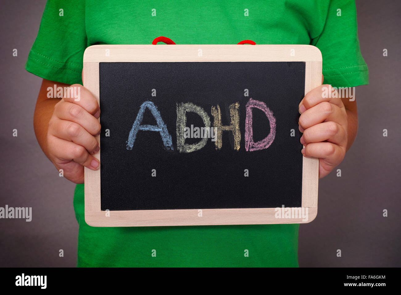 Young boy holds ADHD text written on blackboard. ADHD is Attention ...