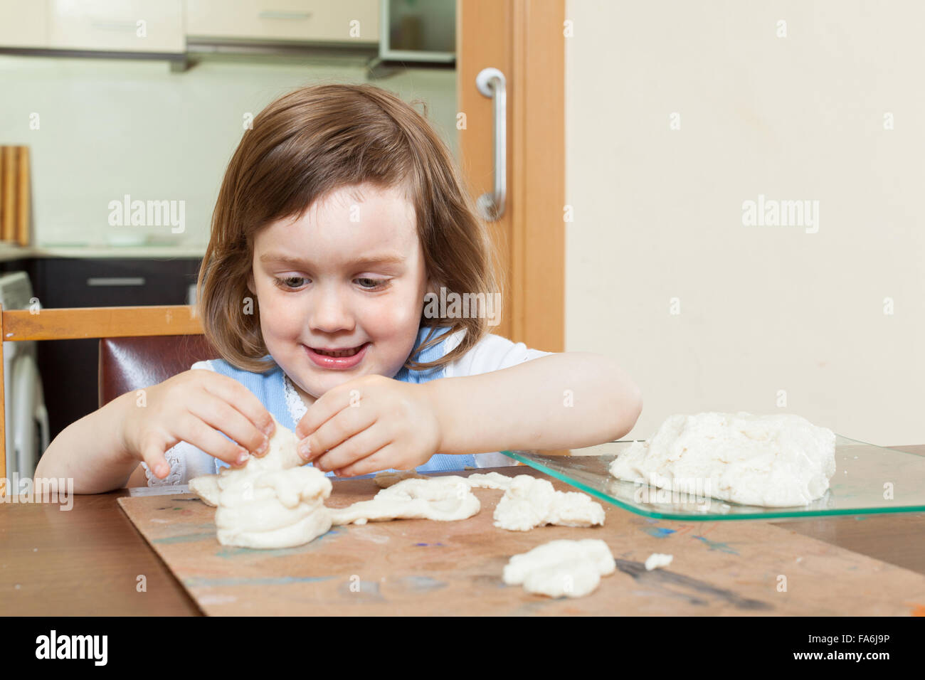 Cute little girl making dough figurines in the room Stock Photo - Alamy