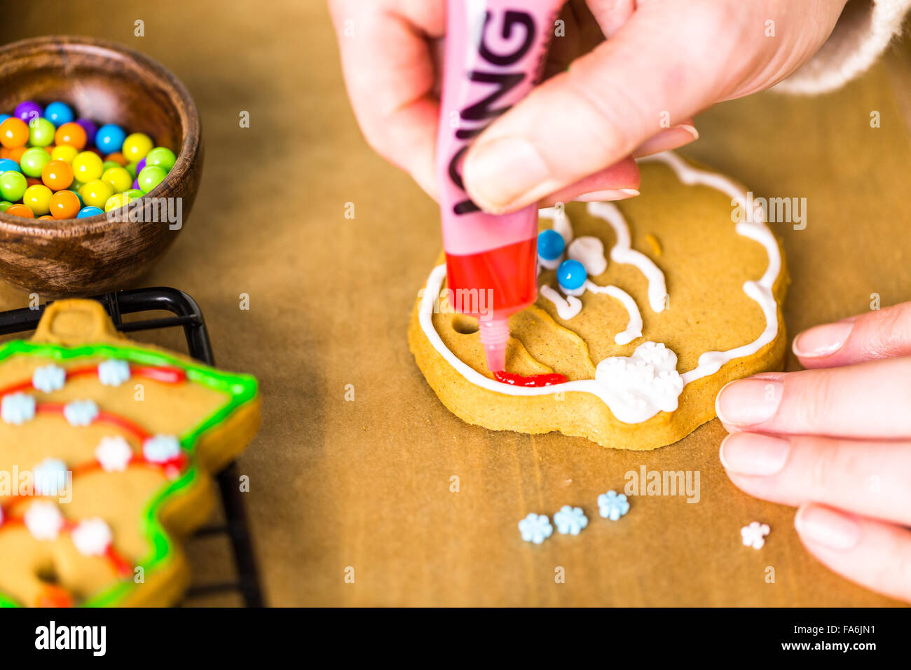 Decorating gingerbread cookies with royal icing and colorful candies ...