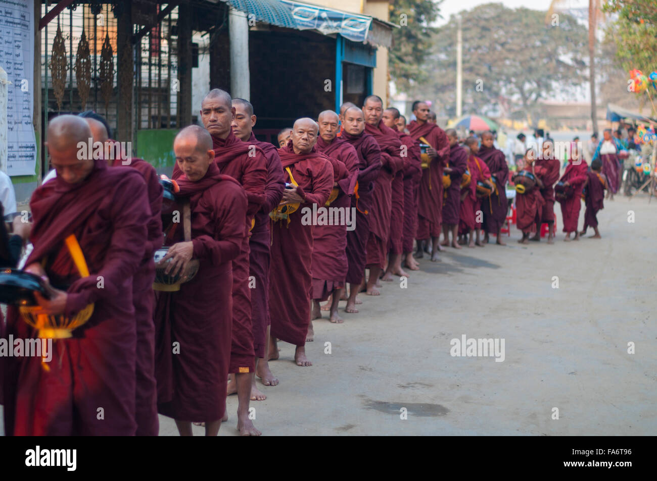 Group of Burmese Buddhist monks on alms round queuing up for food alms ...