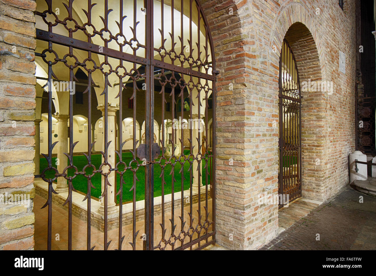 night view of locked gate in front of the portico of a medieval ...