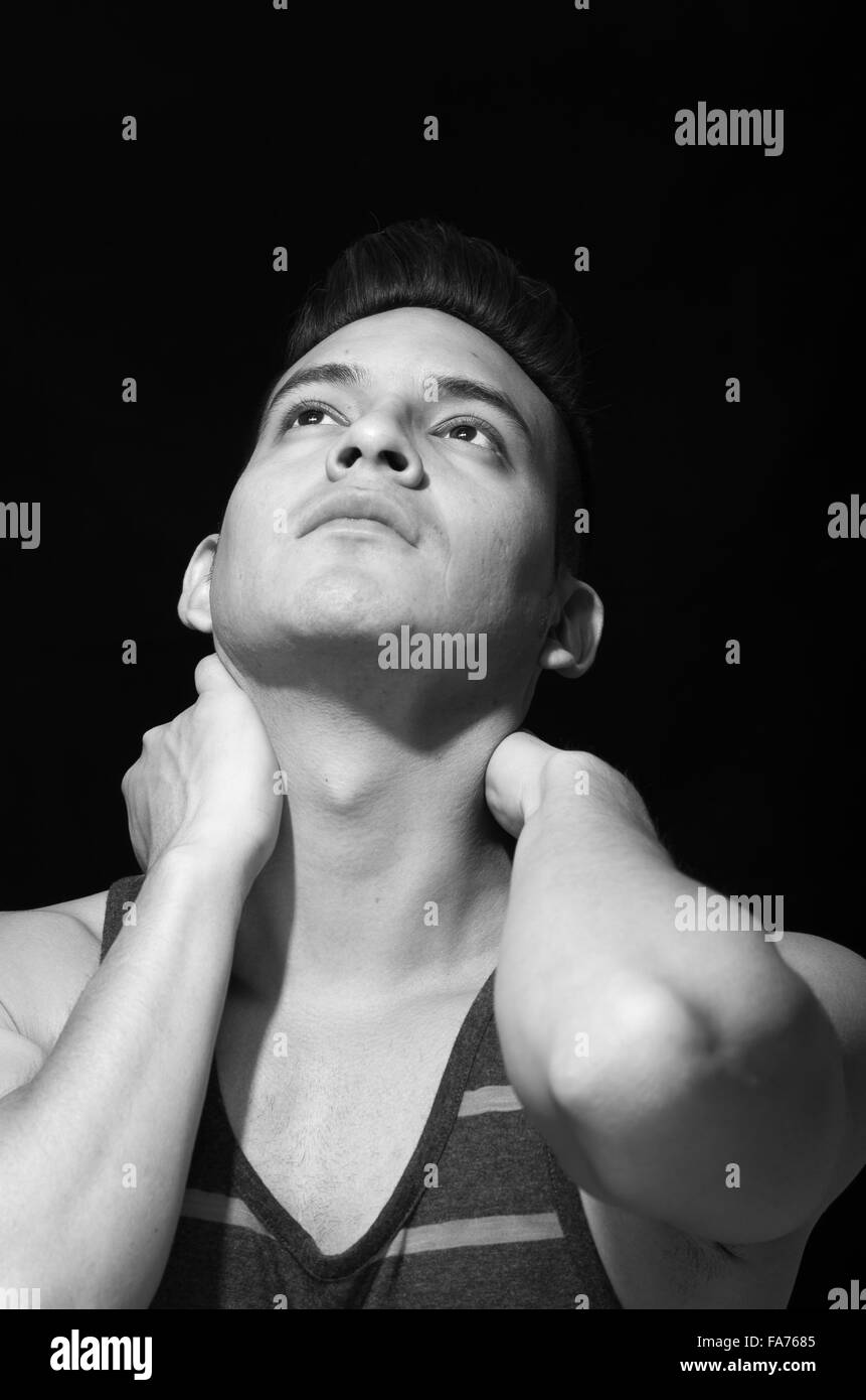 Hispanic male wearing striped singlet touching his own shoulder neck ...