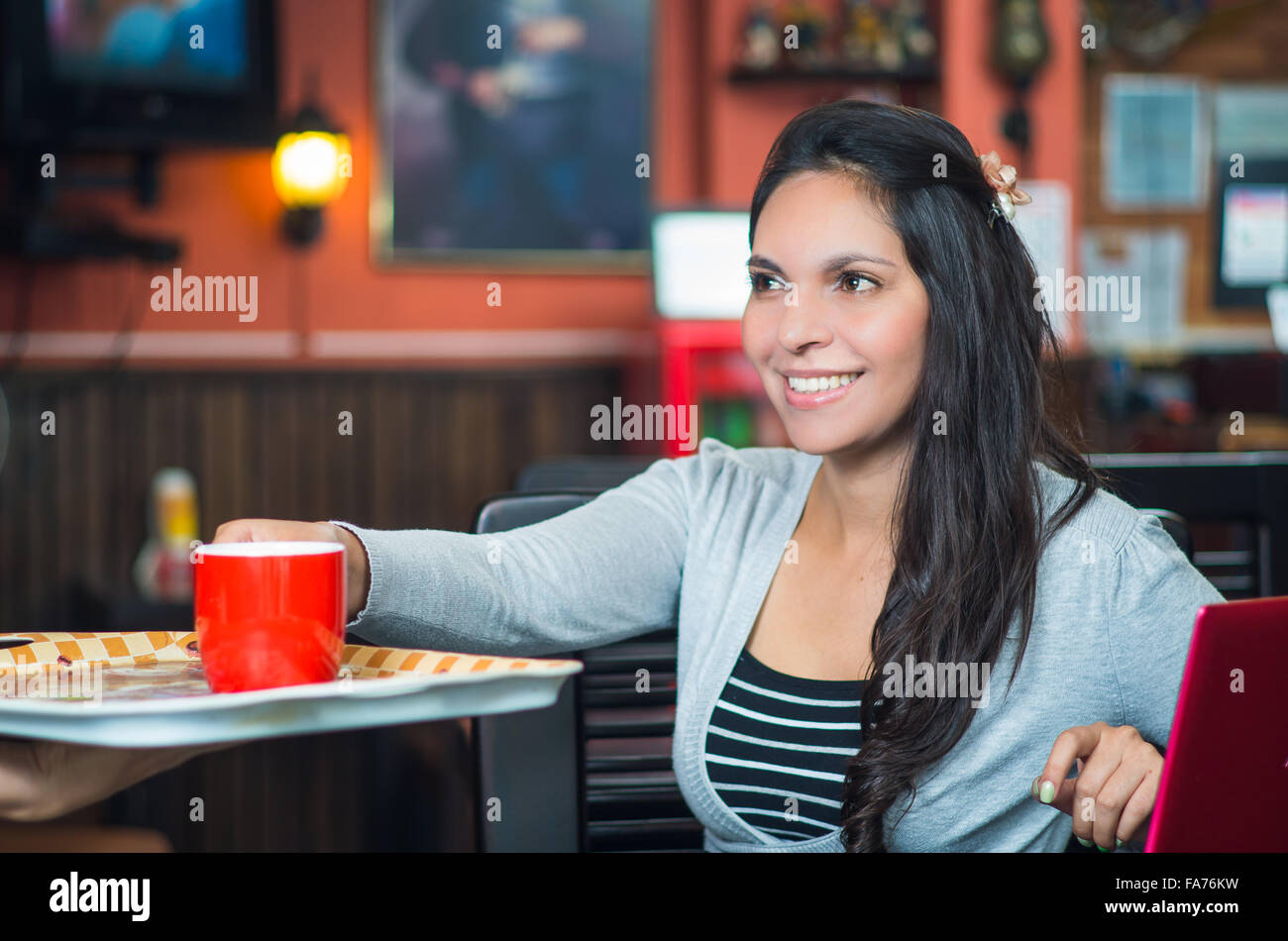 Brunette model sitting at table in restaurant, positive facial ...