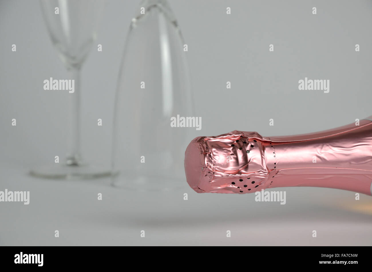 Pink champagne bottleneck with two champagne glasses in background ...