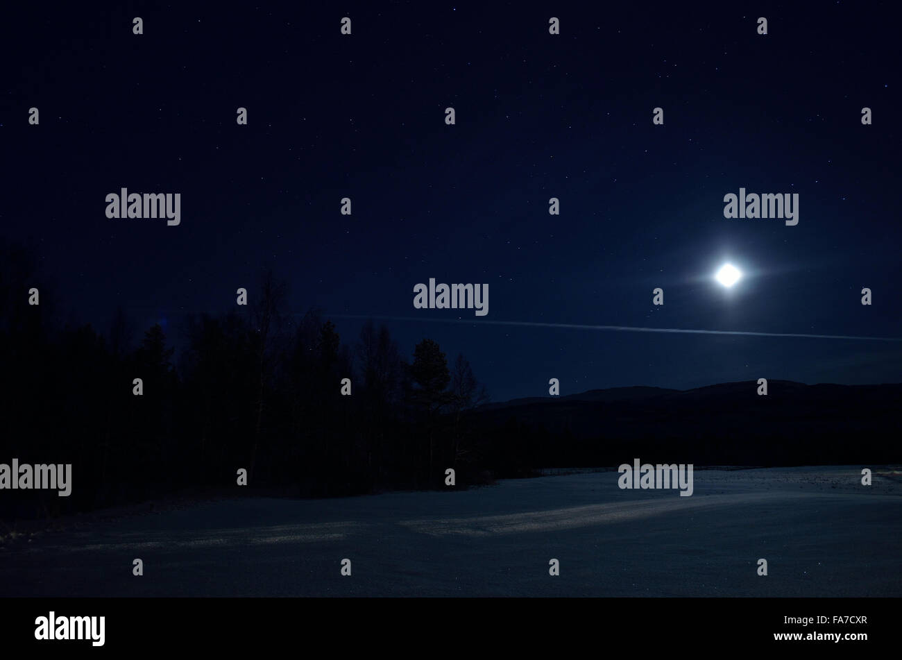 beautiful full moon lights up snowy winter field and star night sky ...