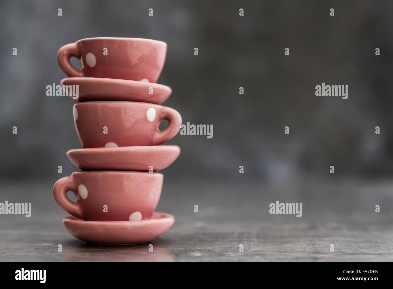 Little pink toy porcelain cups and plates with white dots on gray ...