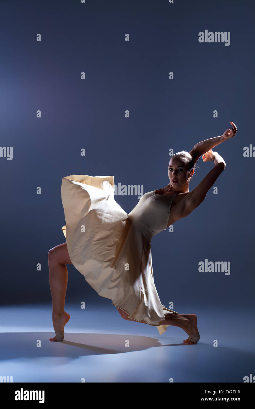 Young beautiful dancer in beige dress dancing on gray background Stock ...