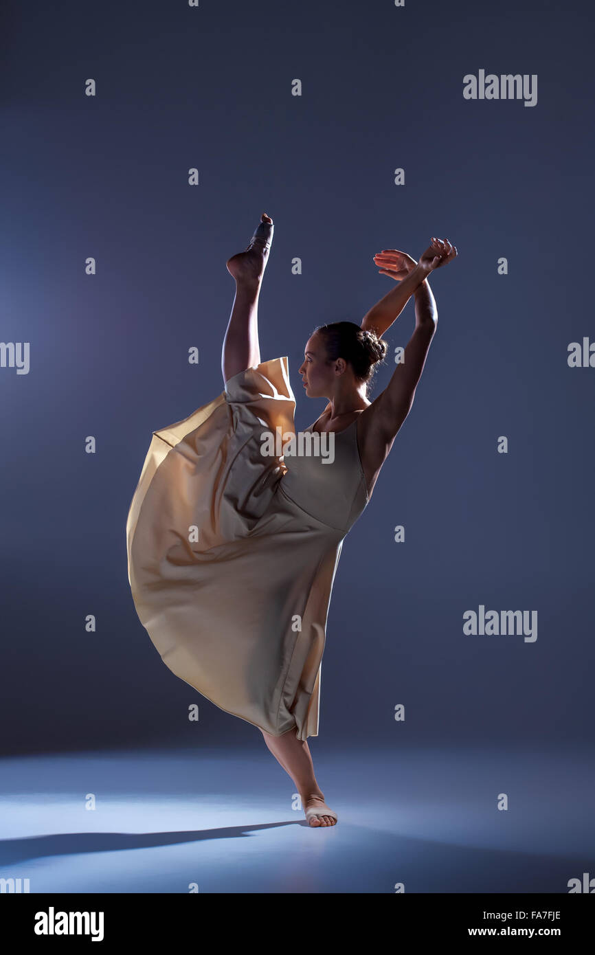 Young beautiful dancer in beige dress dancing on gray background Stock ...