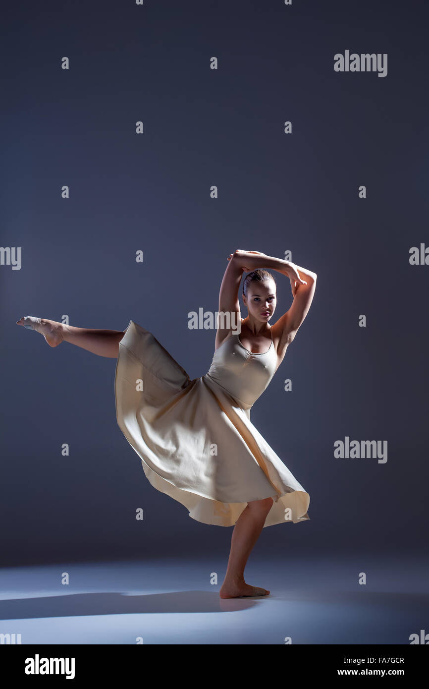 Young beautiful dancer in beige dress dancing on gray background Stock ...