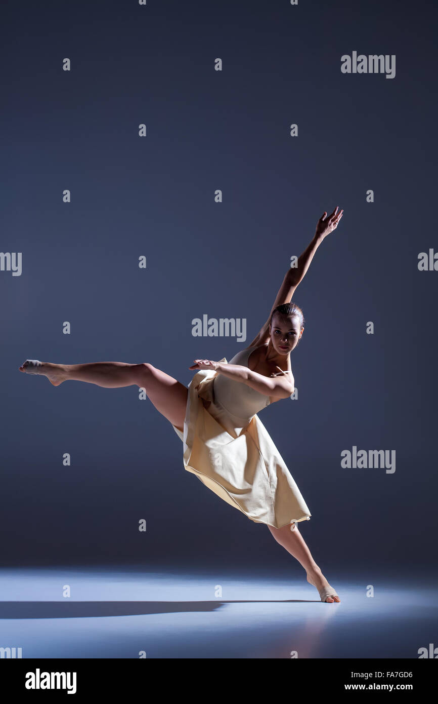 Young beautiful dancer in beige dress dancing on gray background Stock ...