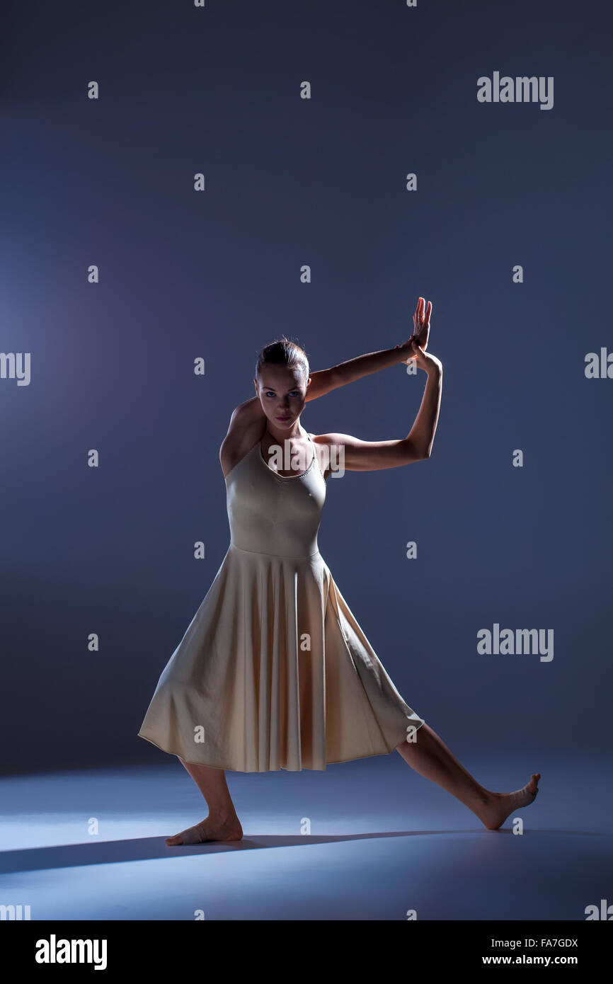 Young beautiful dancer in beige dress dancing on gray background Stock ...