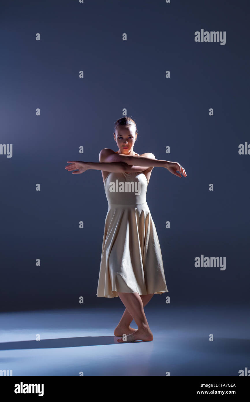 Young beautiful dancer in beige dress dancing on gray background Stock ...