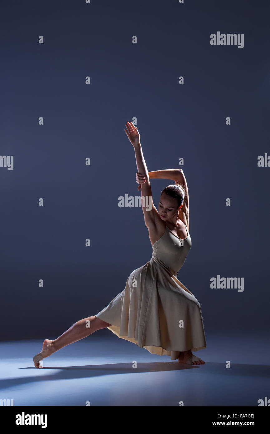 Young beautiful dancer in beige dress dancing on gray background Stock ...