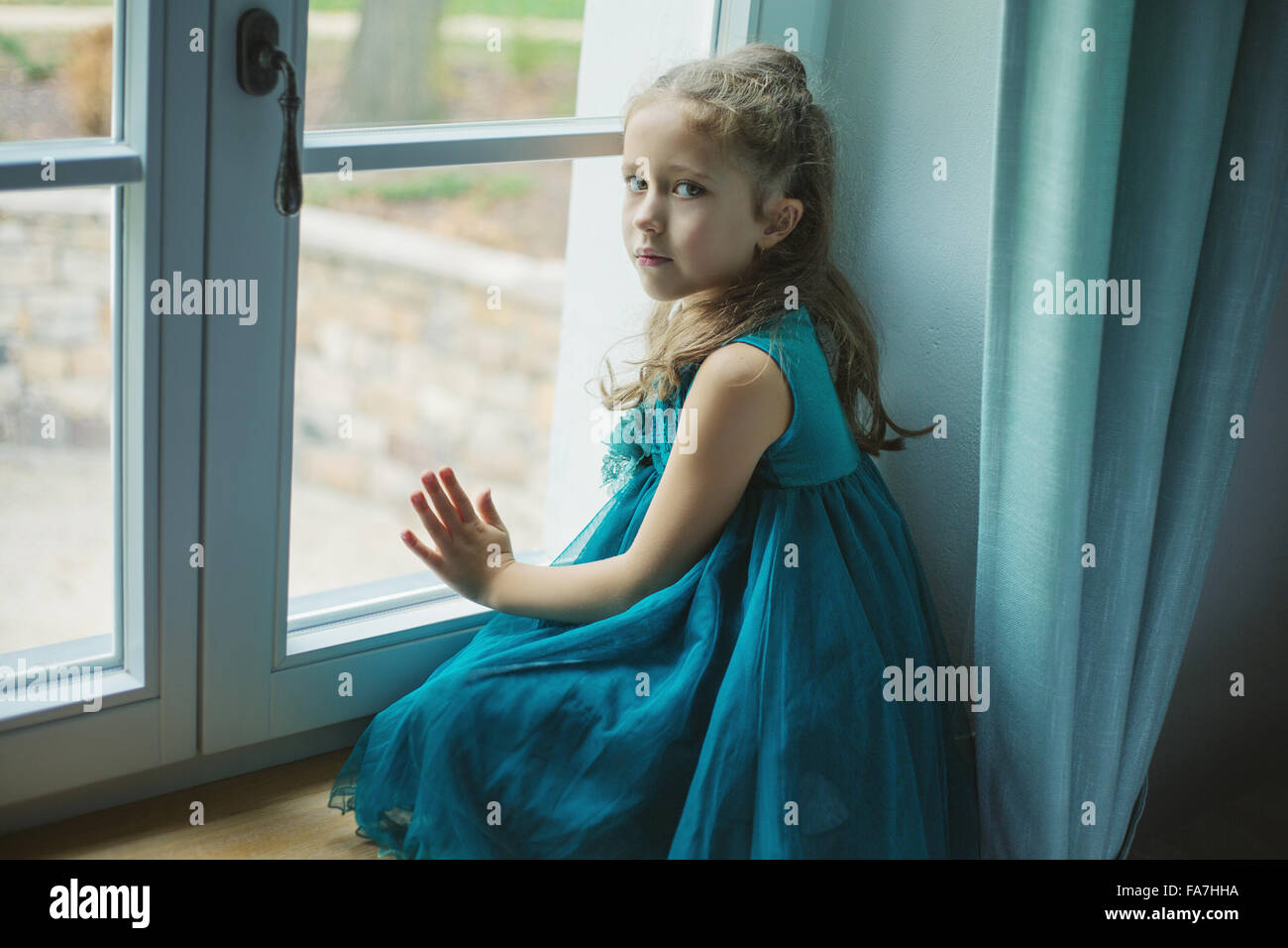Sad girl looking through window Stock Photo - Alamy