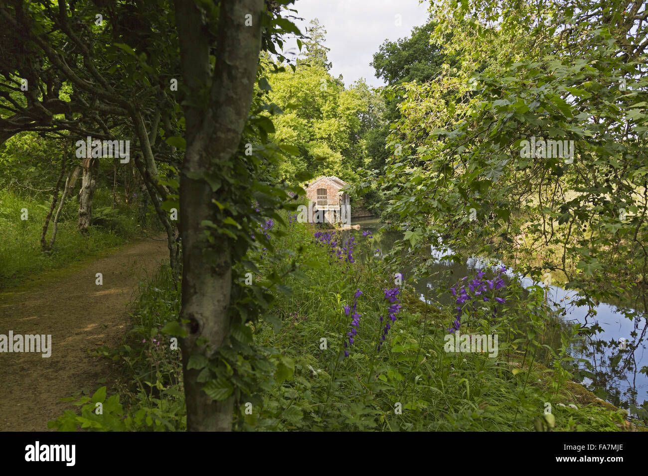 The riverside path at Woolbeding Gardens, West Sussex. Woolbeding is a ...