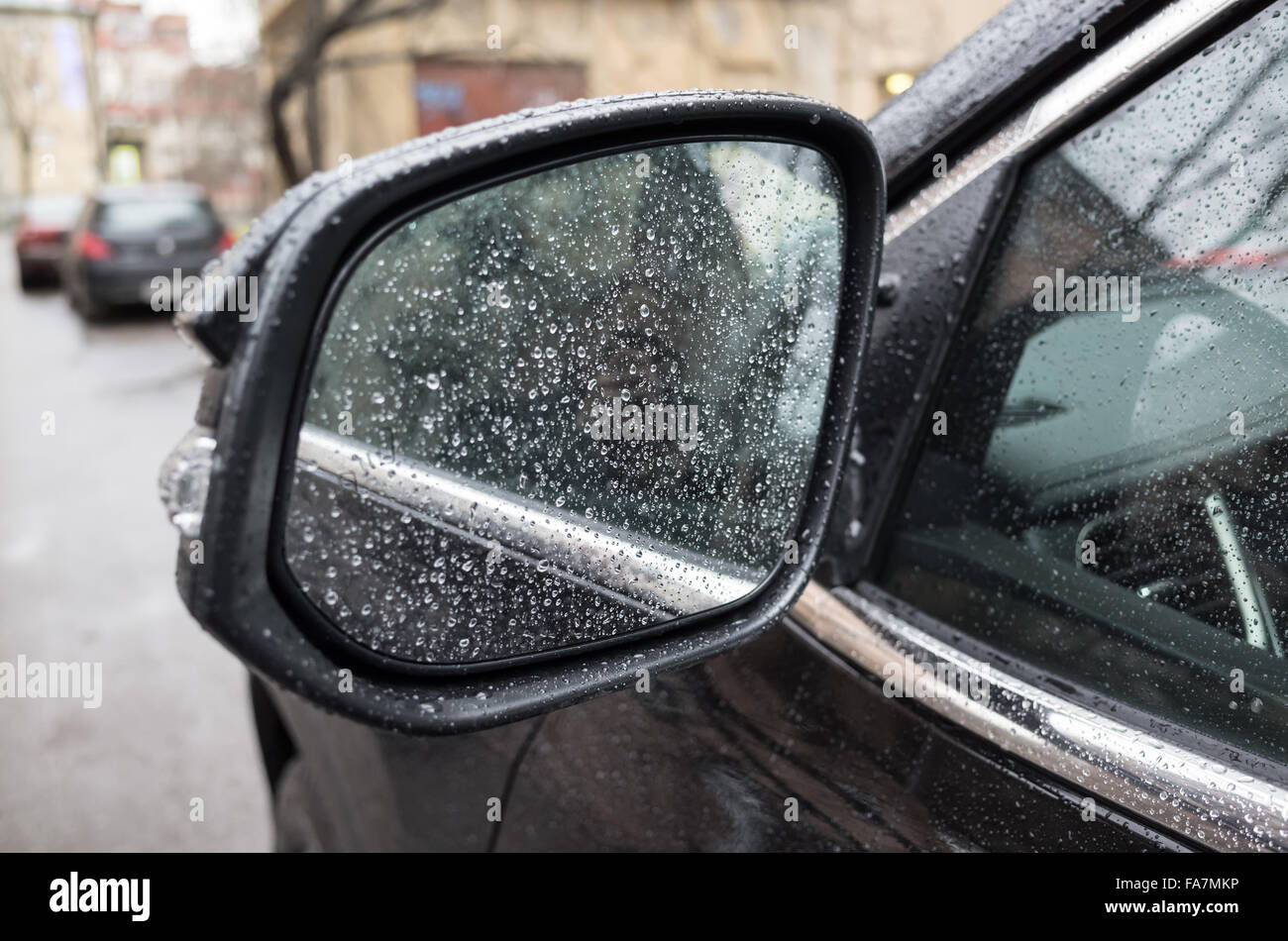 Wet black shining car mirror with raindrops. Closeup photo with ...