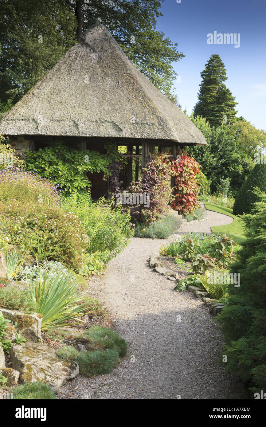 A gravel path sweeps around the thatched Hawk House in the gardens of ...
