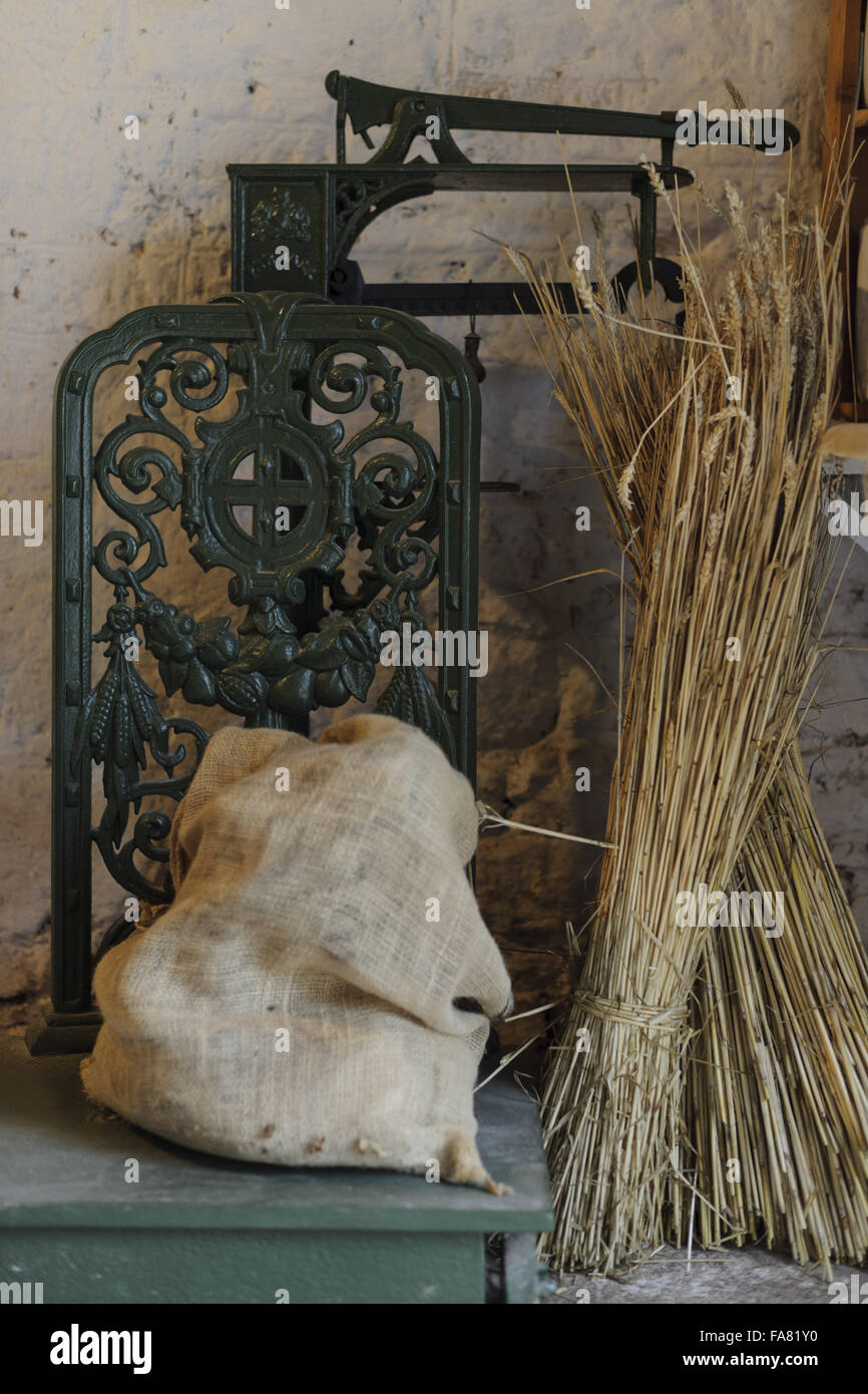Sheaves of wheat beside a sack of grain on wrought iron scales, at ...