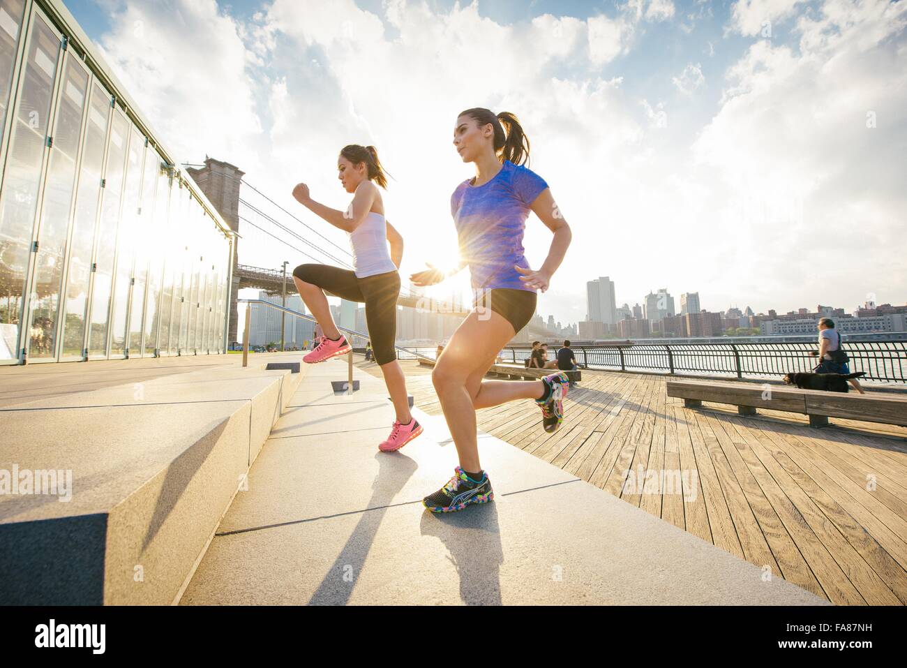 Two female running friends running up stairs on riverside, New York ...