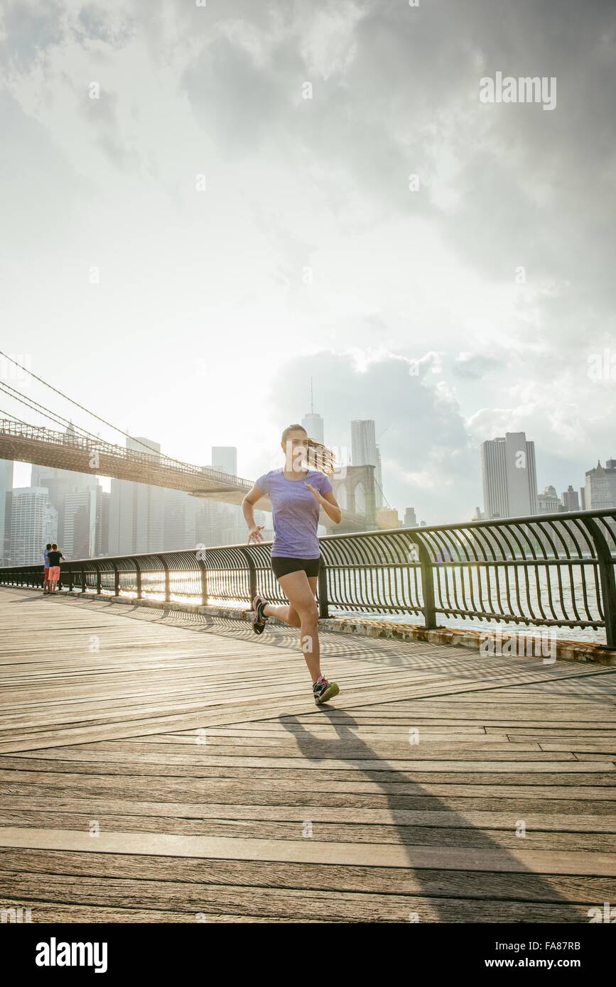 Young female runner running along riverside, Brooklyn, New York, USA ...