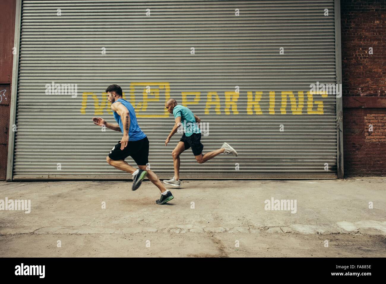 Two young male runners running on city street Stock Photo - Alamy