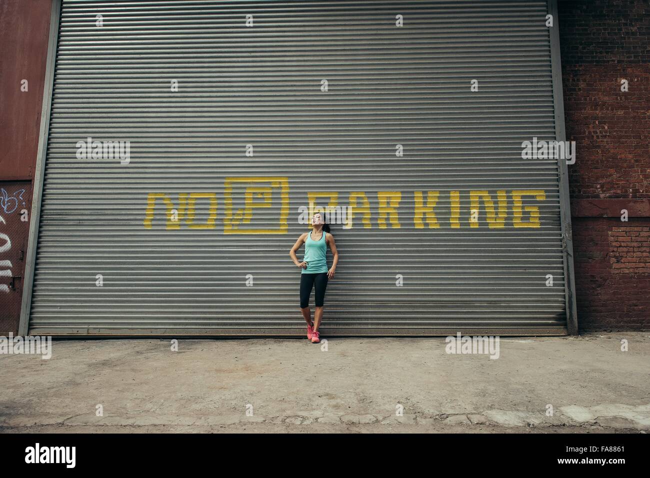 Young female runner leaning against shutter Stock Photo - Alamy