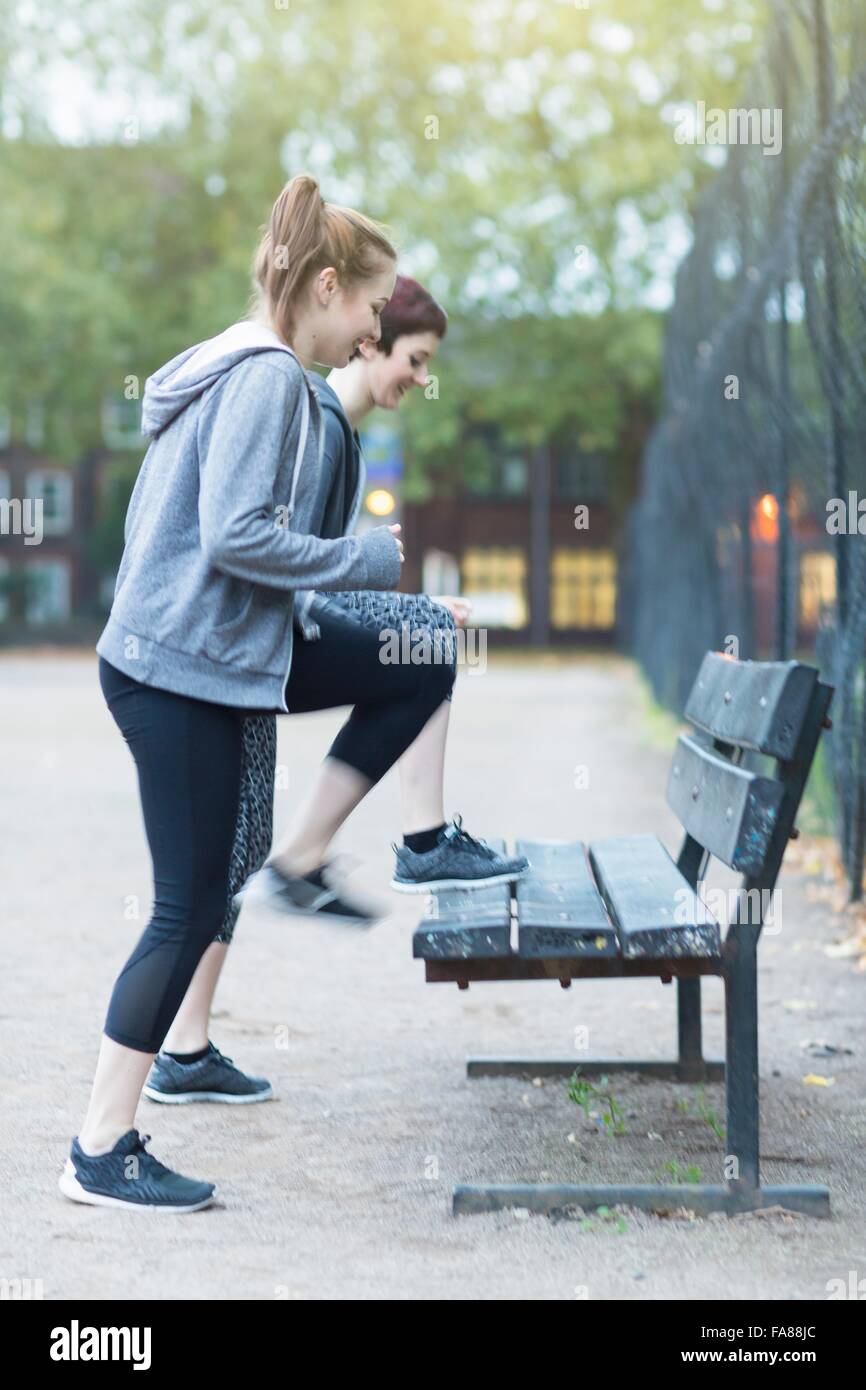 Side view of young women exercising, step up on park bench Stock Photo ...