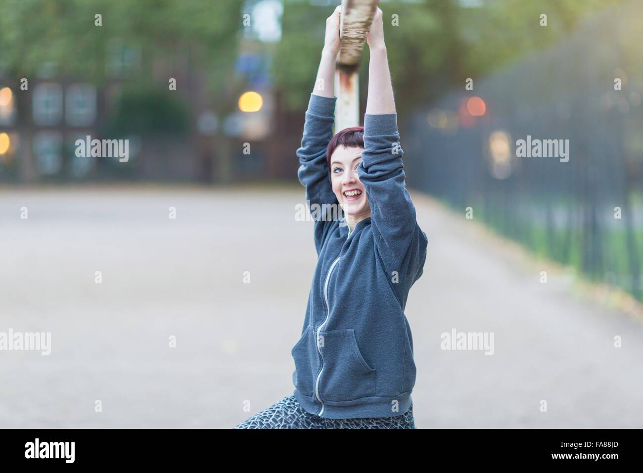 Young woman arms raised holding goal post looking at camera smiling ...