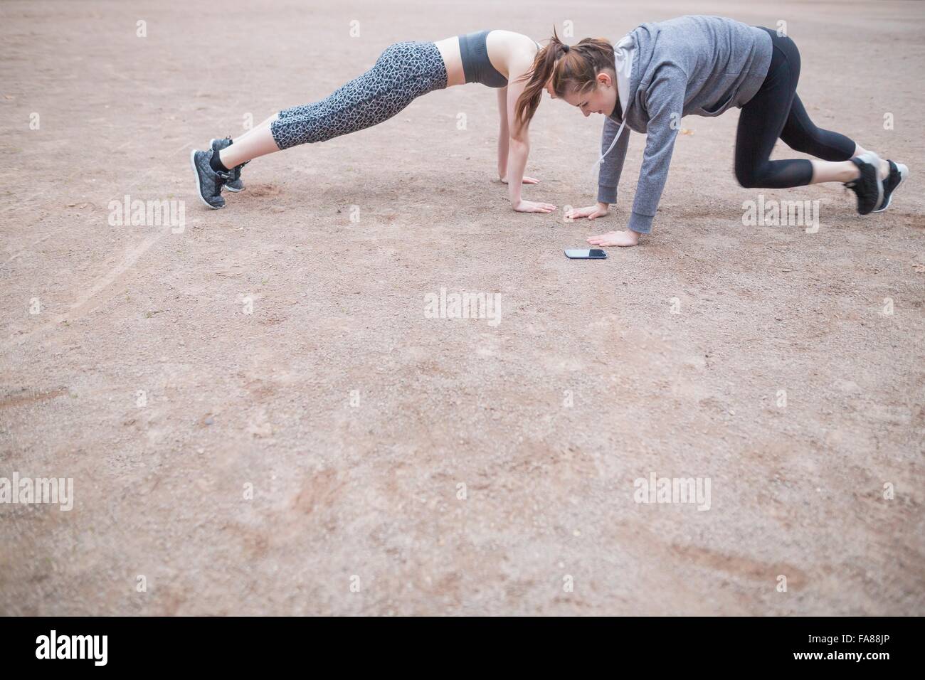 Side view of young women leaning on hands looking down exercising on ...