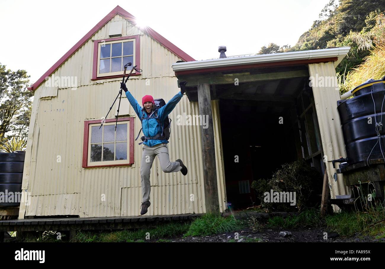 Female hiker jumping mid air outside house, Tararua Ridge, New Zealand ...