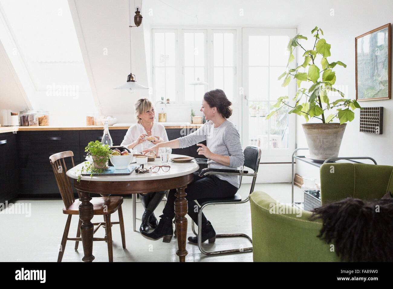 Two mature women sitting at kitchen table, having tea Stock Photo - Alamy
