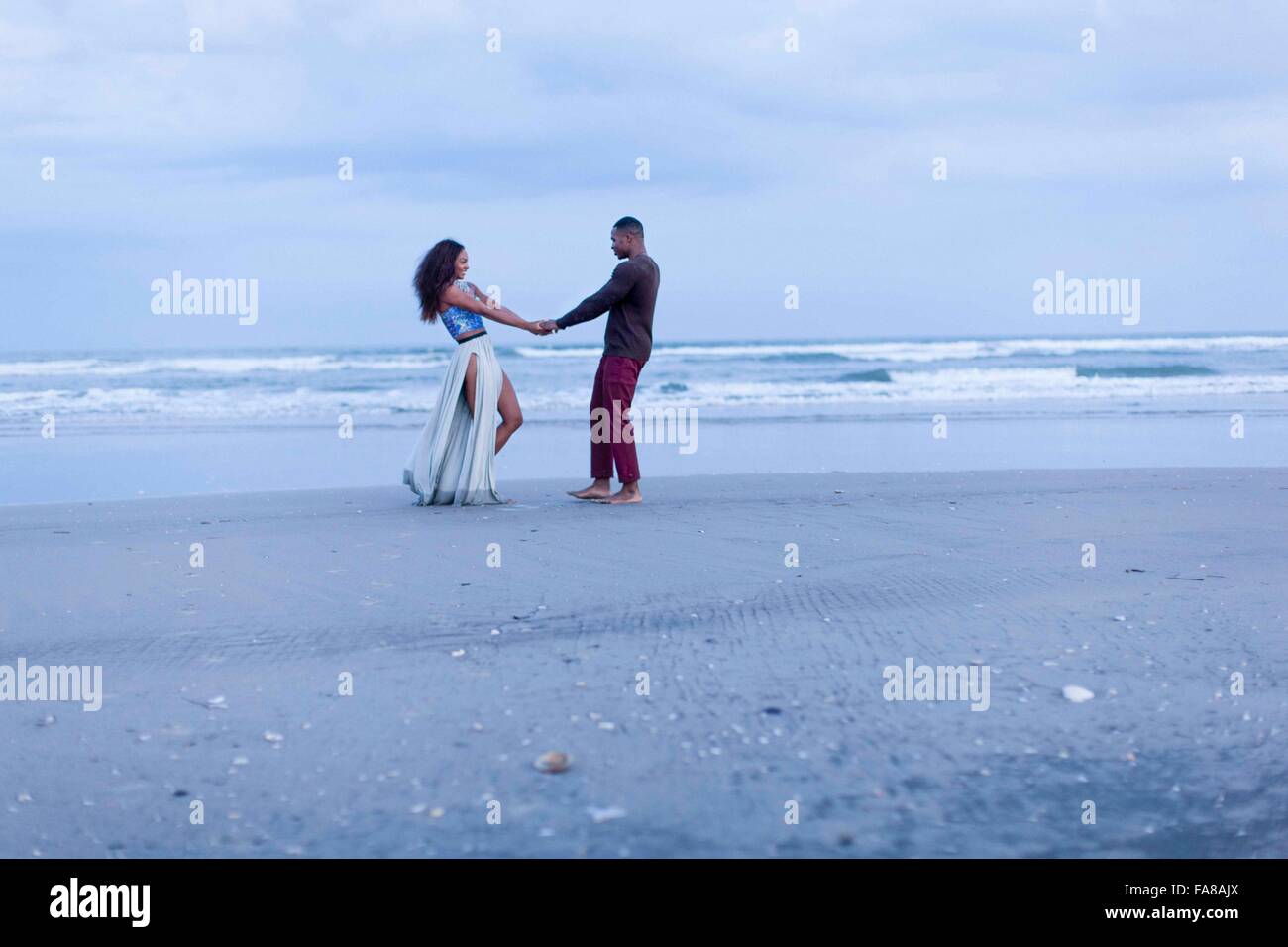 Couple fooling around on beach, holding hands Stock Photo - Alamy